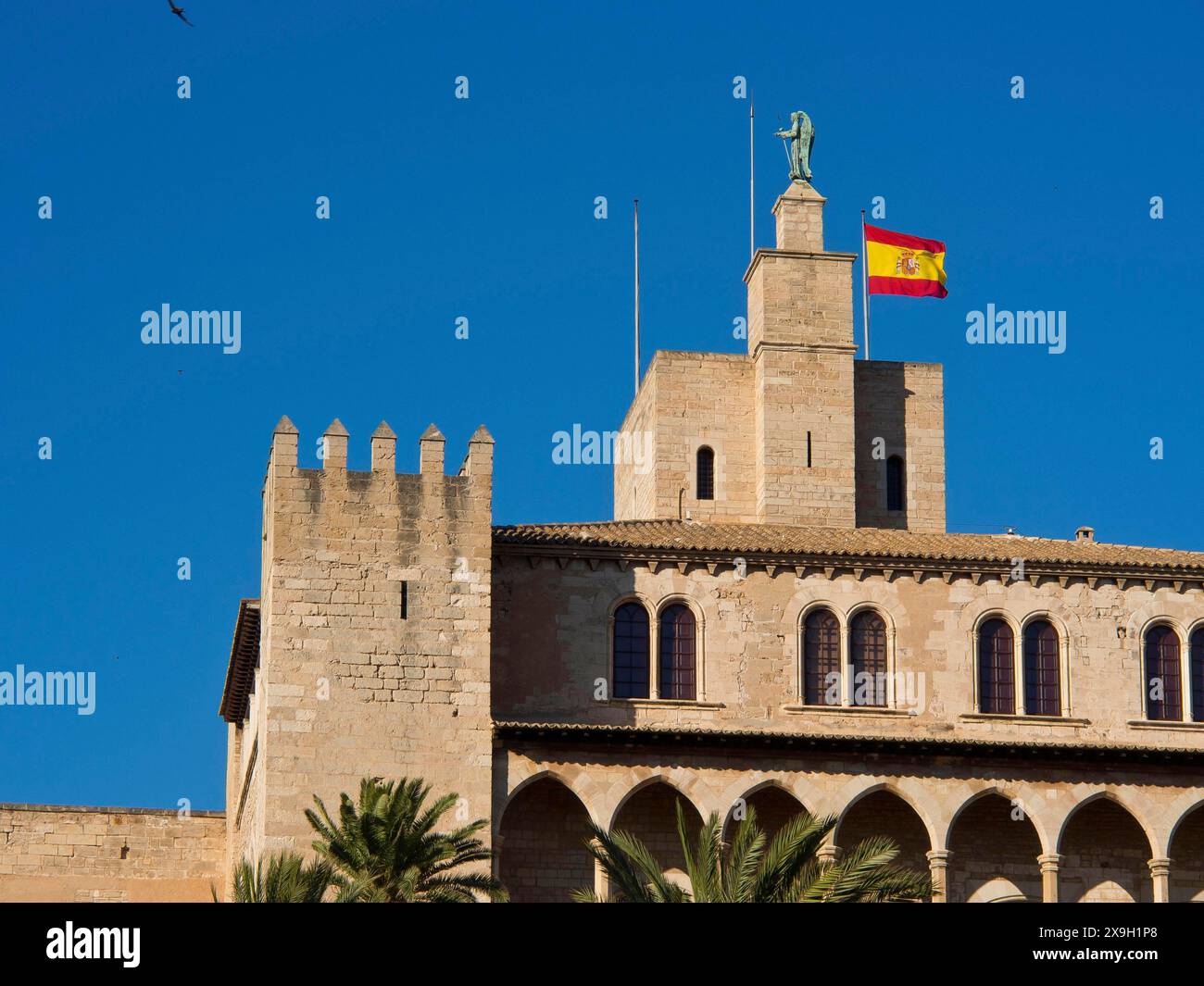 Historic building with stone tower and Spanish flag under a blue sky ...
