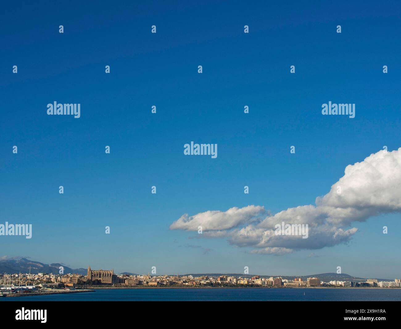A wide blue sky with scattered clouds and a city view on the horizon ...