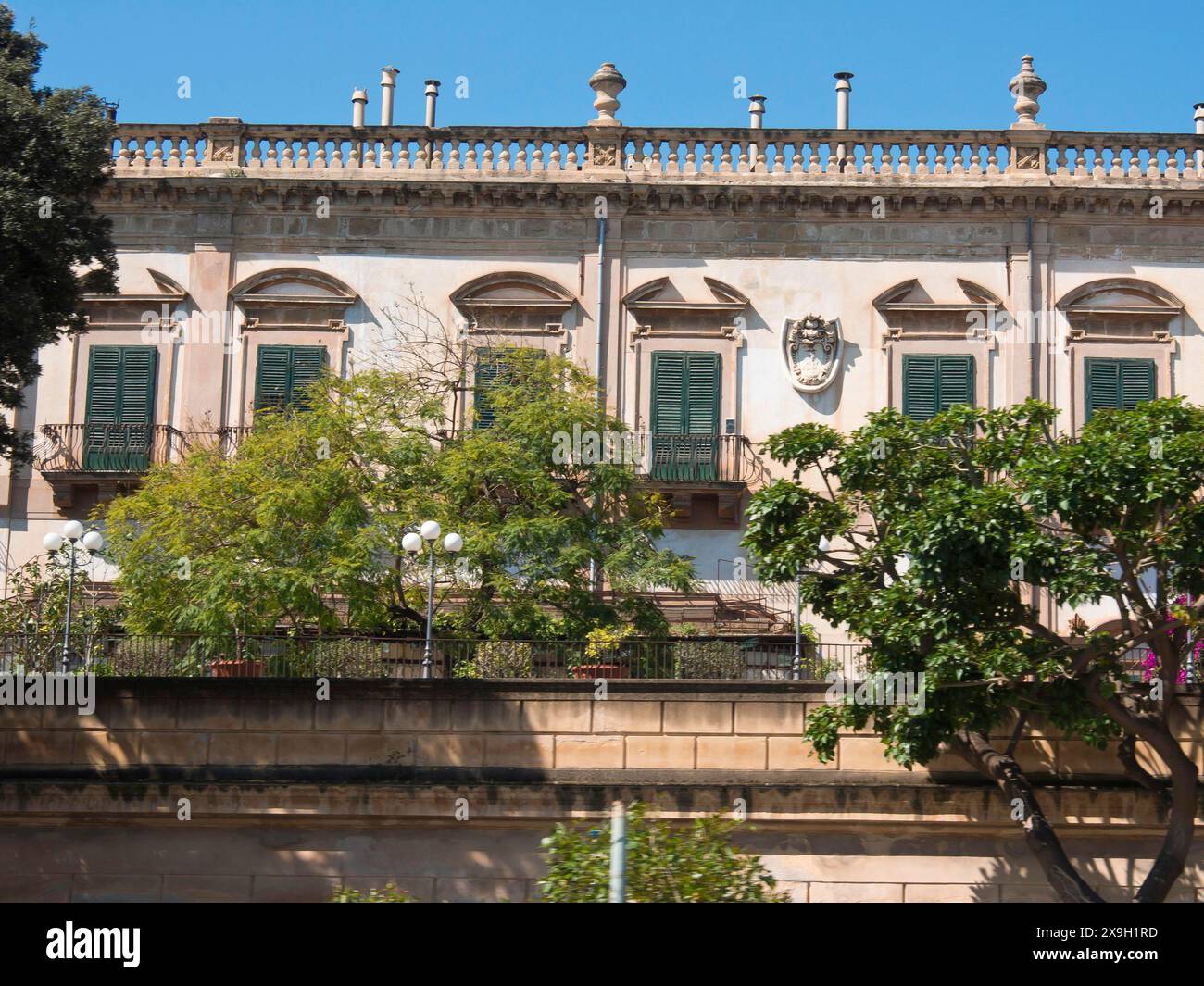 Historic building with green shutters and garden in a sunny setting ...