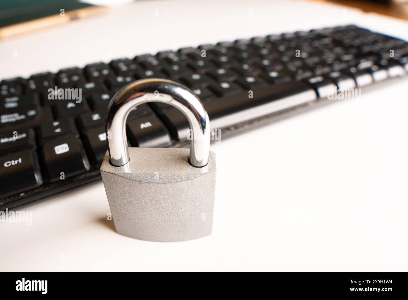 A closed padlock next to a computer keyboard on a white background with ...