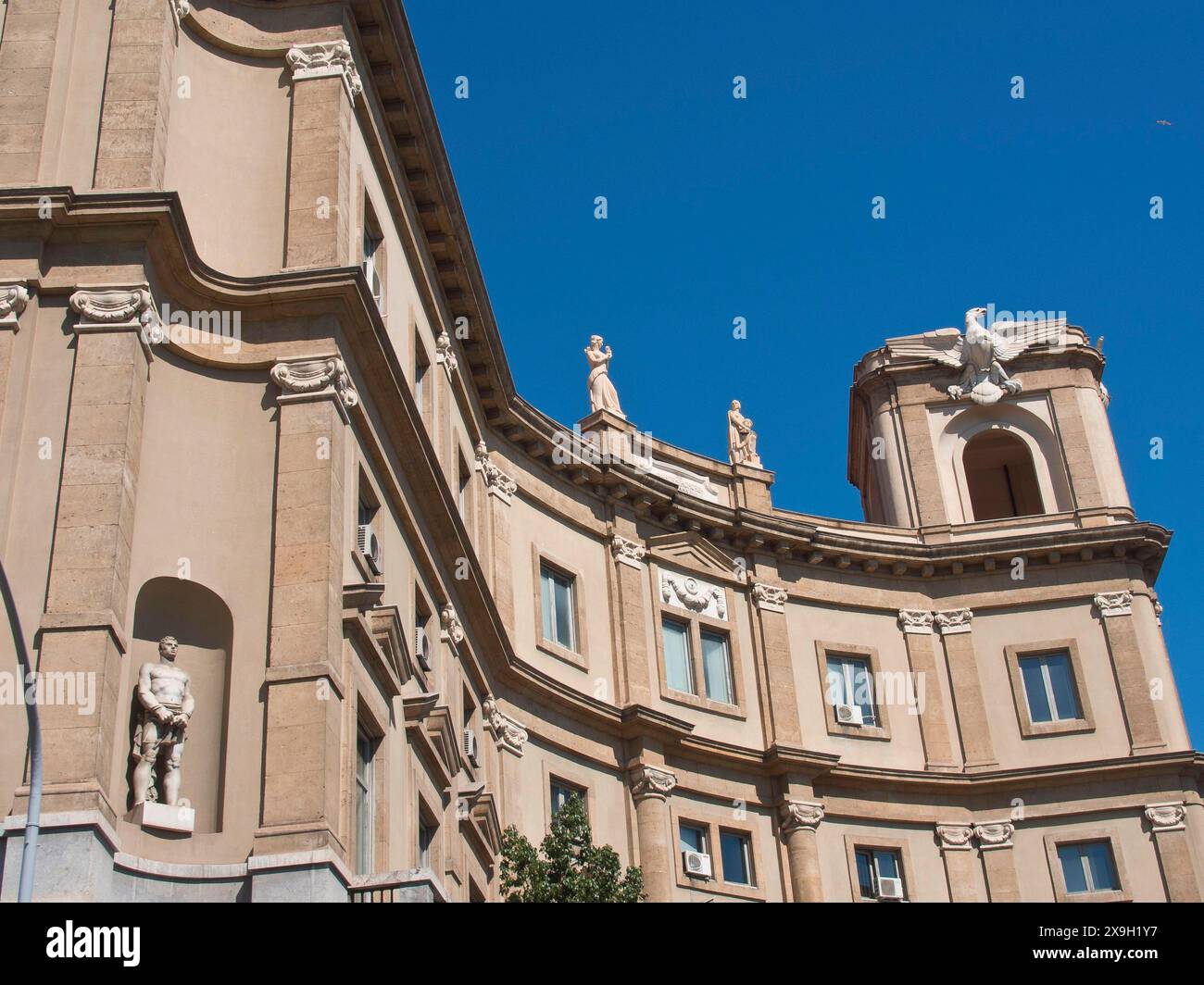 Classical building with several statues in front of a bright blue sky ...