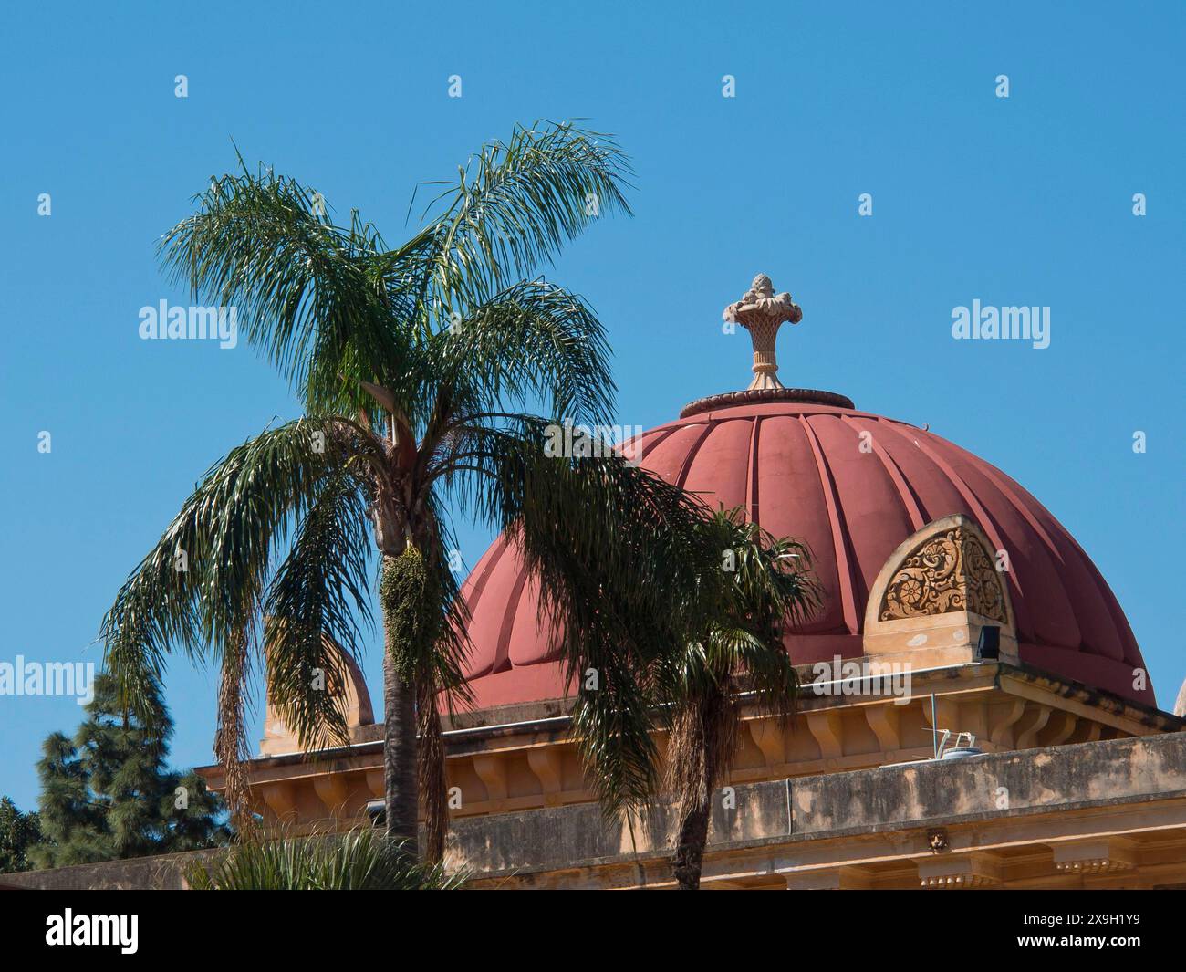 Historic building with red dome behind palm trees in front of a bright ...