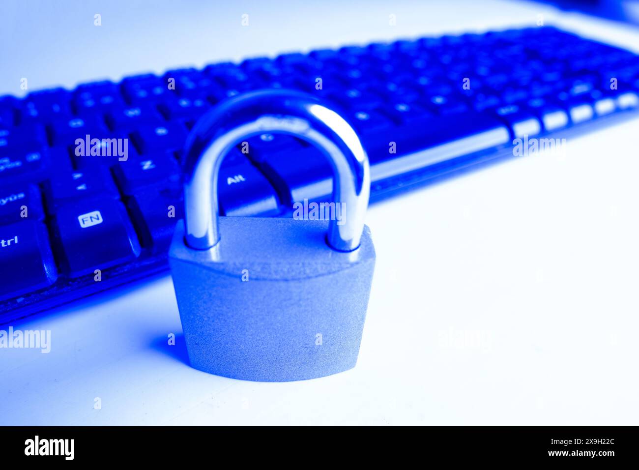 A closed padlock next to a computer keyboard on a white background with ...