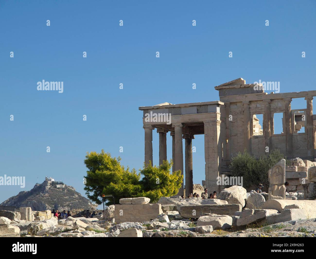 Ancient temple ruins with columns surrounded by trees under a clear sky ...