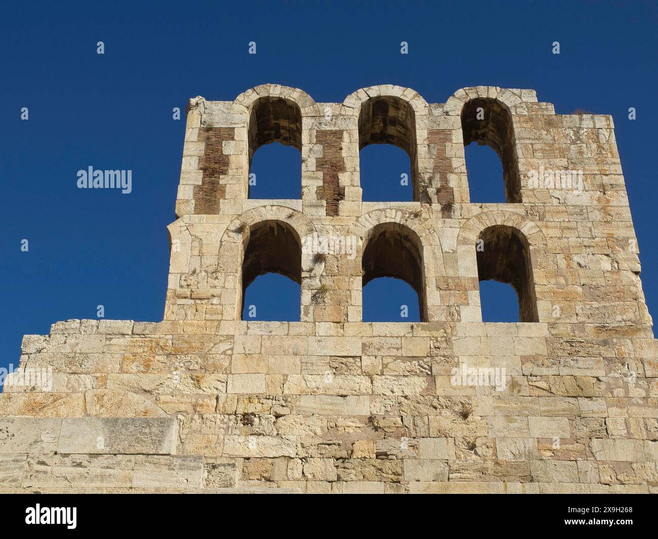 Ancient wall with arches and striking masonry against a blue sky ...