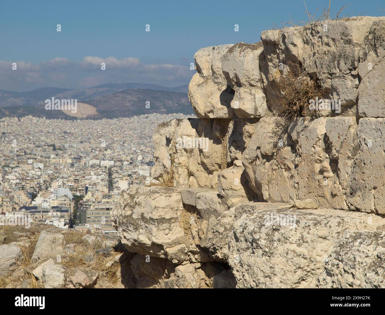 Large ancient stones on a hill overlooking a modern city under a blue ...