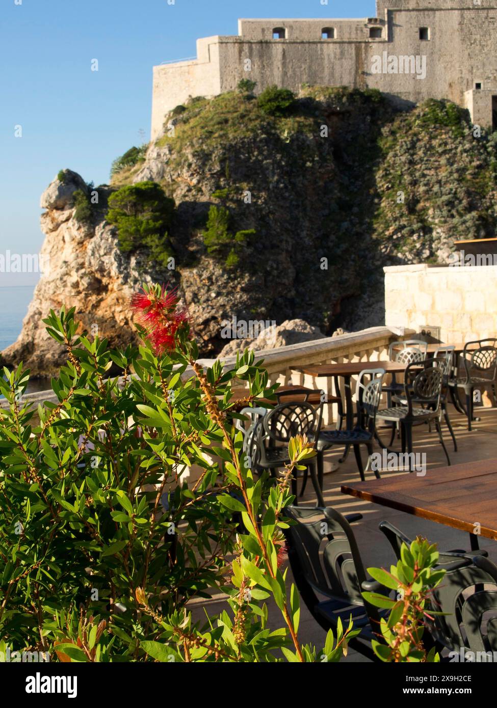 Terrace with chairs and tables next to a rock formation with sea view ...