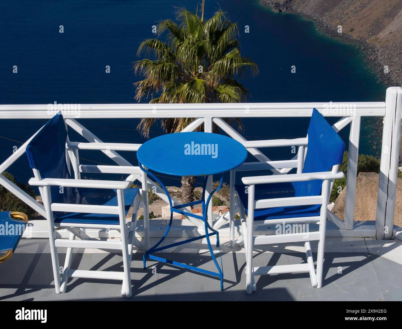 Two white chairs and blue table on a balcony with sea view and palm ...