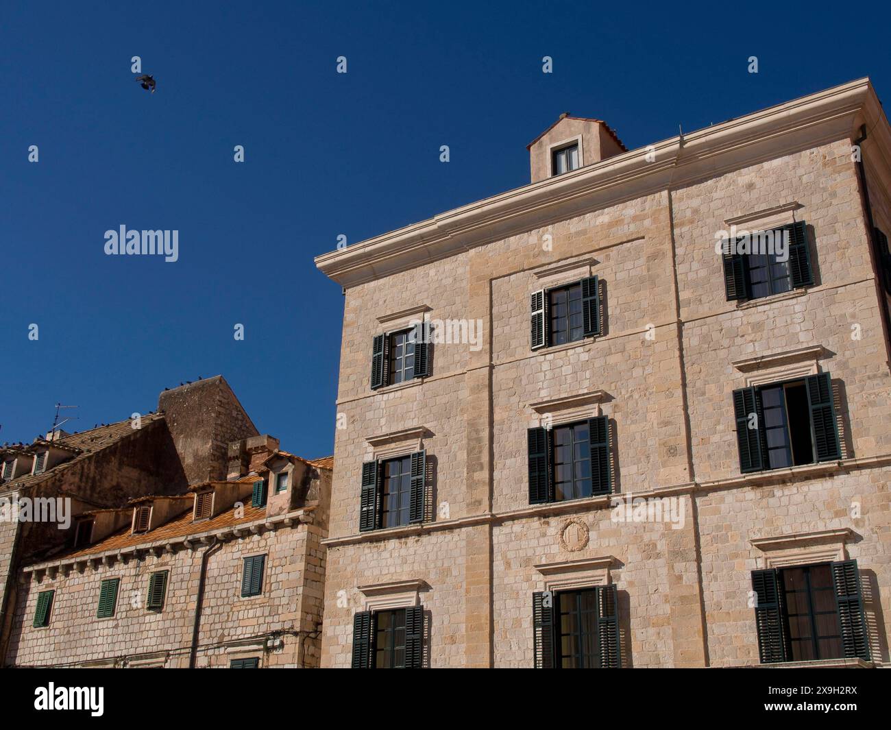 Multi-storey building with green shutters against a clear sky, the old ...