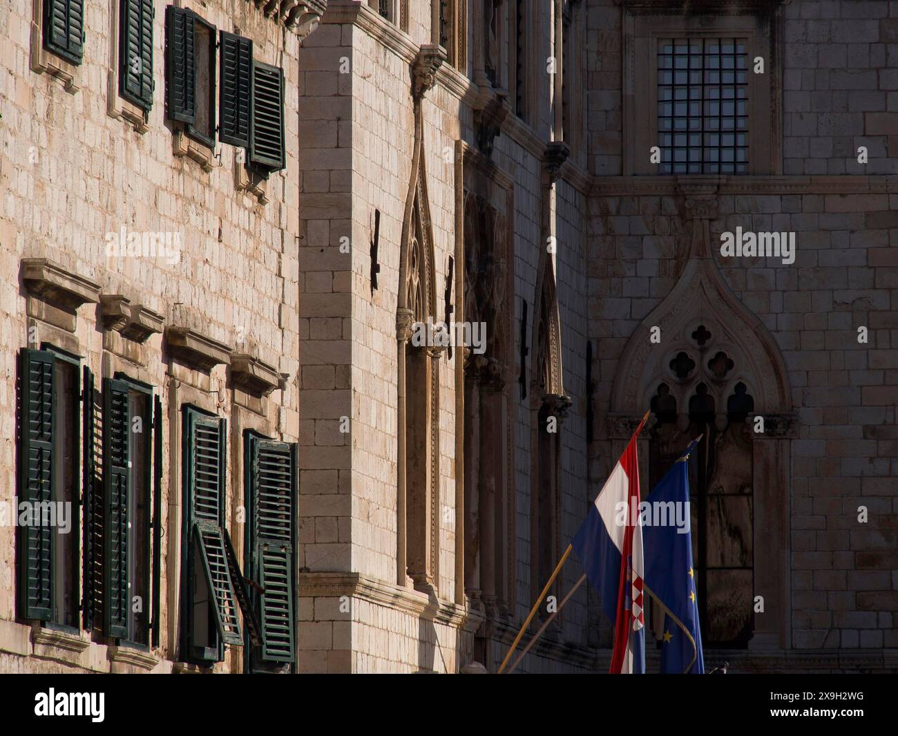 Detail of a historic stone facade with gothic style elements and flags ...
