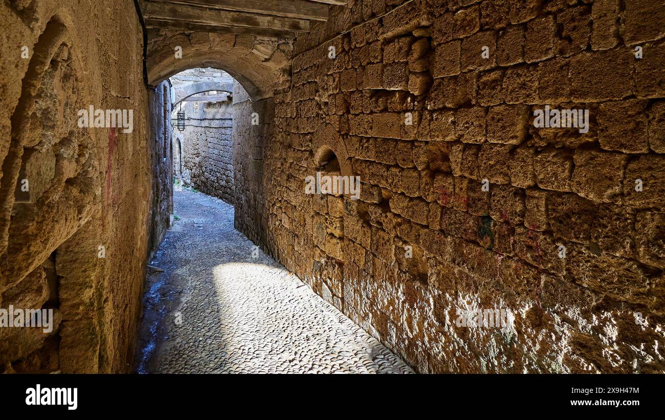 A narrow alleyway with stone walls, flooded with light and shadow, Old ...