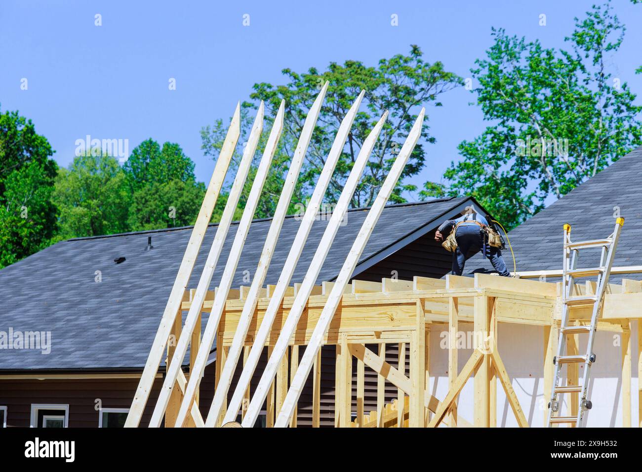 Worker installing beams using an air hammer while nailing wooden plank ...