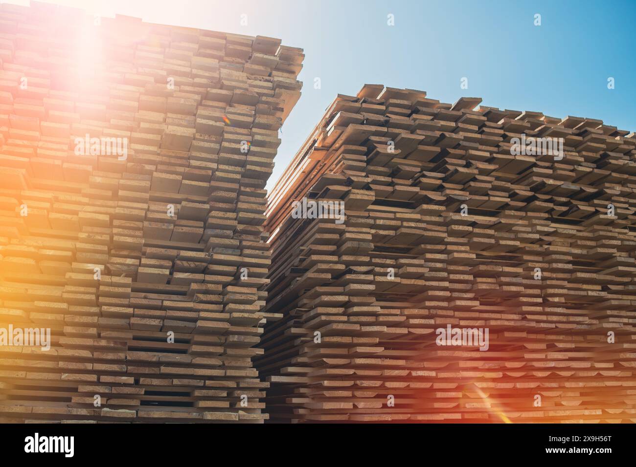 A large stack of lumber boards is neatly stacked at a lumber yard. The ...
