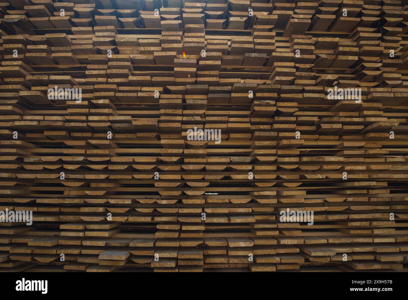 A large stack of lumber boards is neatly stacked at a lumber yard. The ...