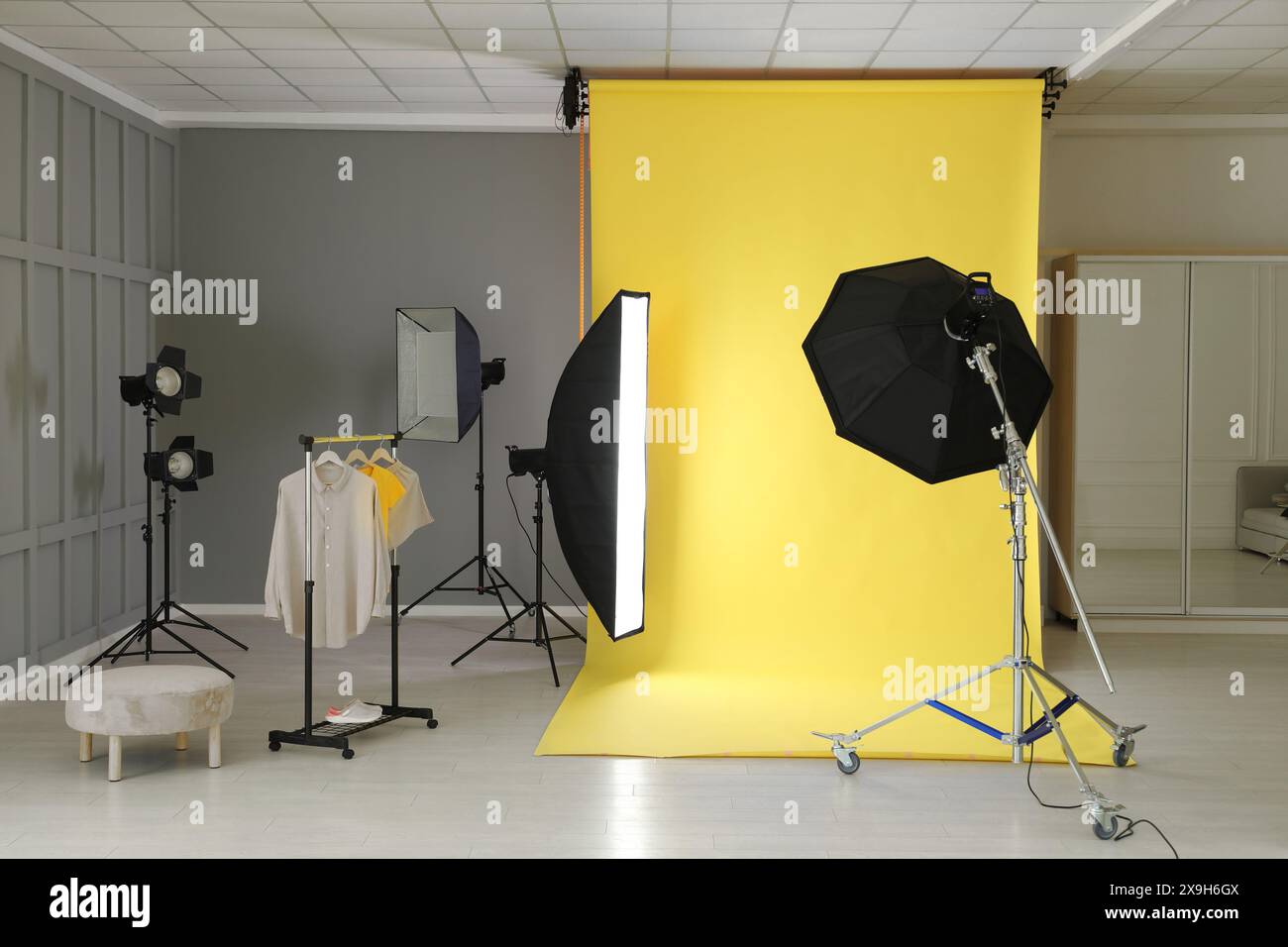 Yellow photo background, rack with clothes and professional lighting ...