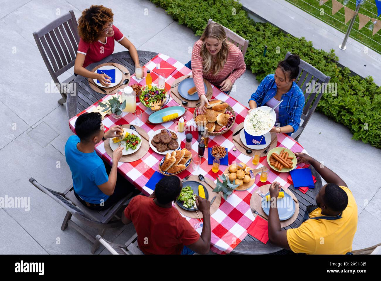 Happy diverse group of friends talking and having dinner at balcony ...