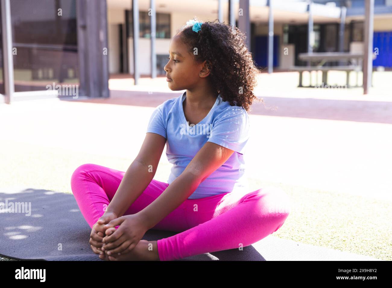 Biracial girl sits cross-legged outdoors at school Stock Photo - Alamy