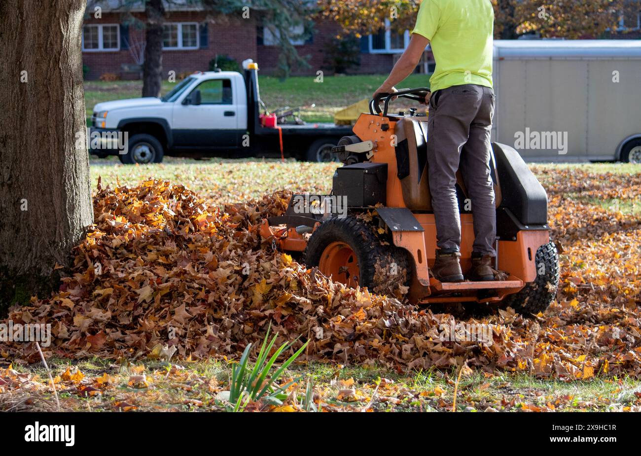 A worker uses a lawn leaf machine to mulch up leaves and to clean up ...