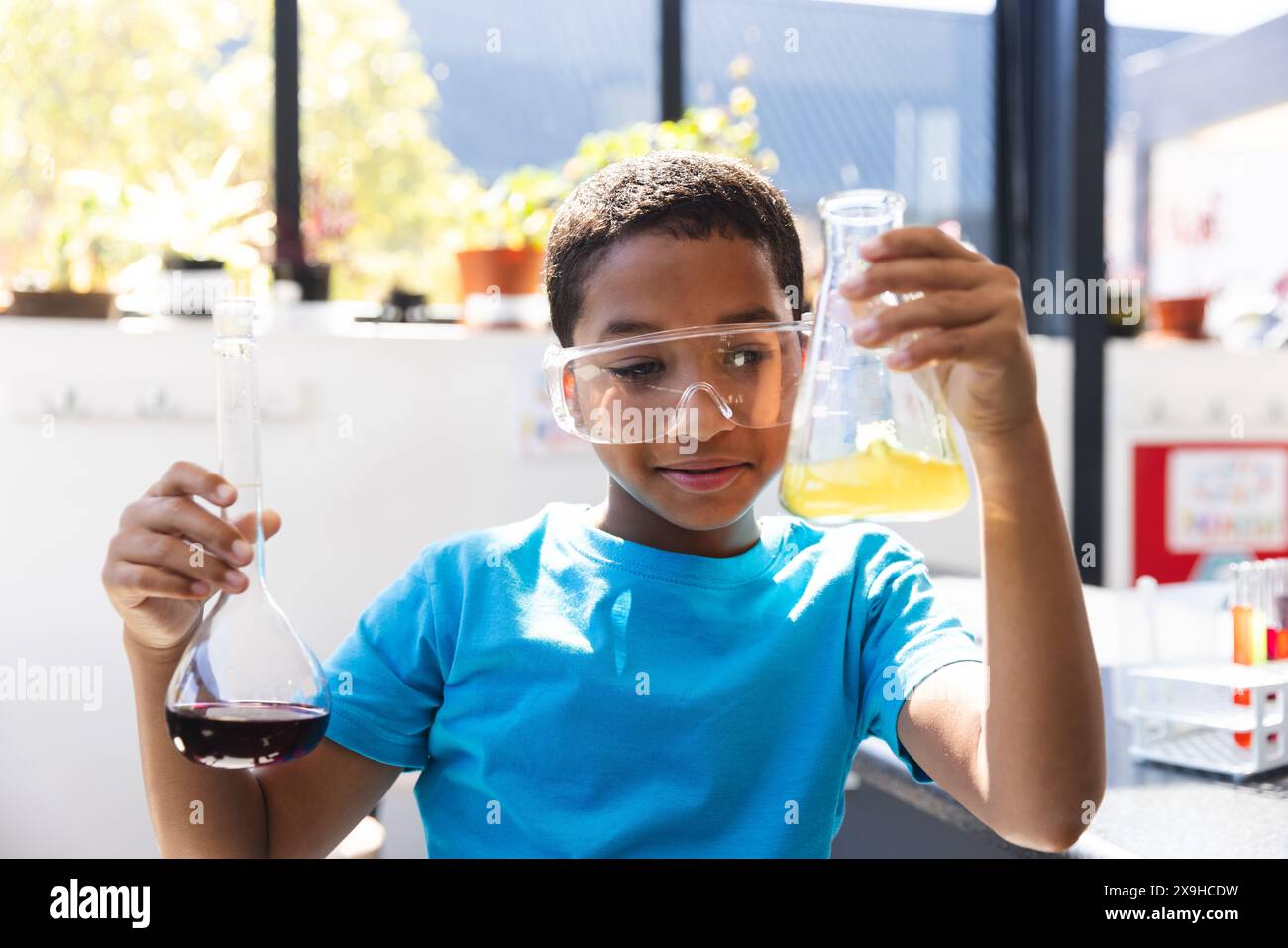 Biracial boy examines science experiment at school in the classroom ...