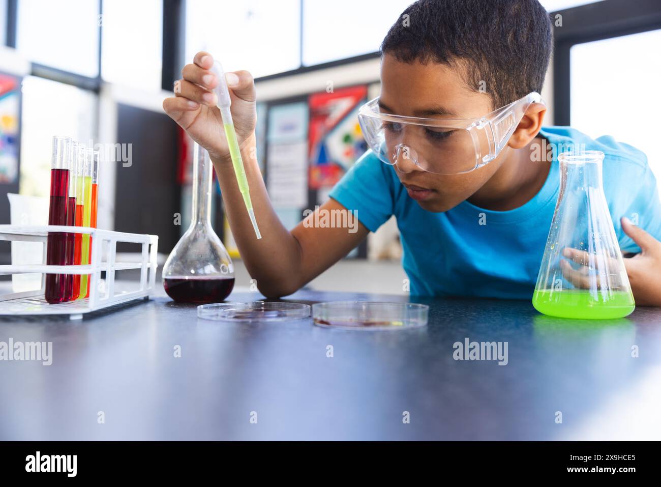 Biracial boy engages in a science experiment at school in the classroom ...