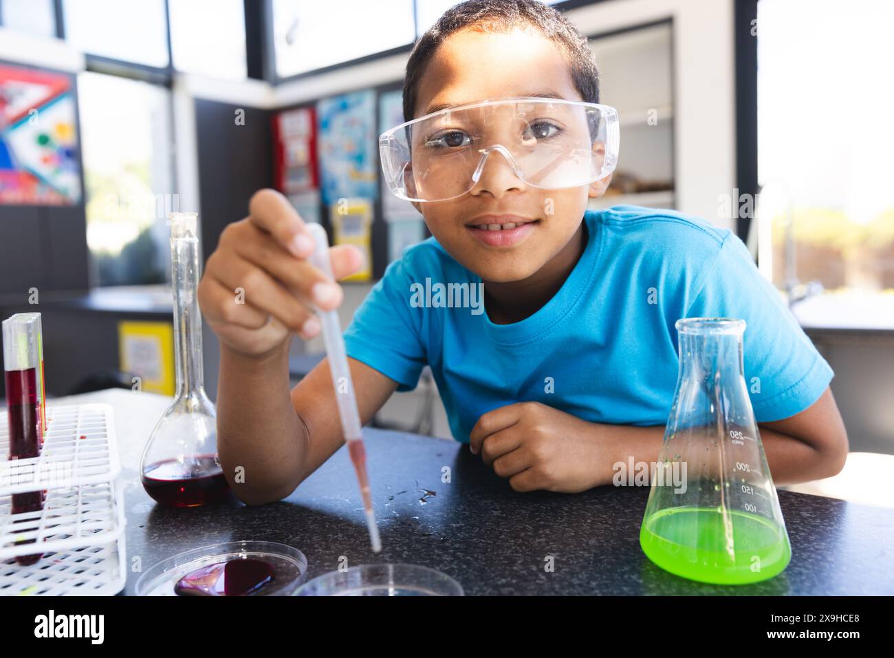 Biracial boy engages in a science experiment at school in the classroom ...