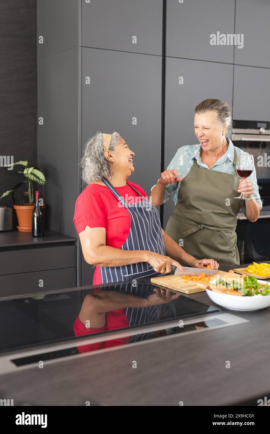 Diverse senior female friends cooking, laughing together at home Stock ...