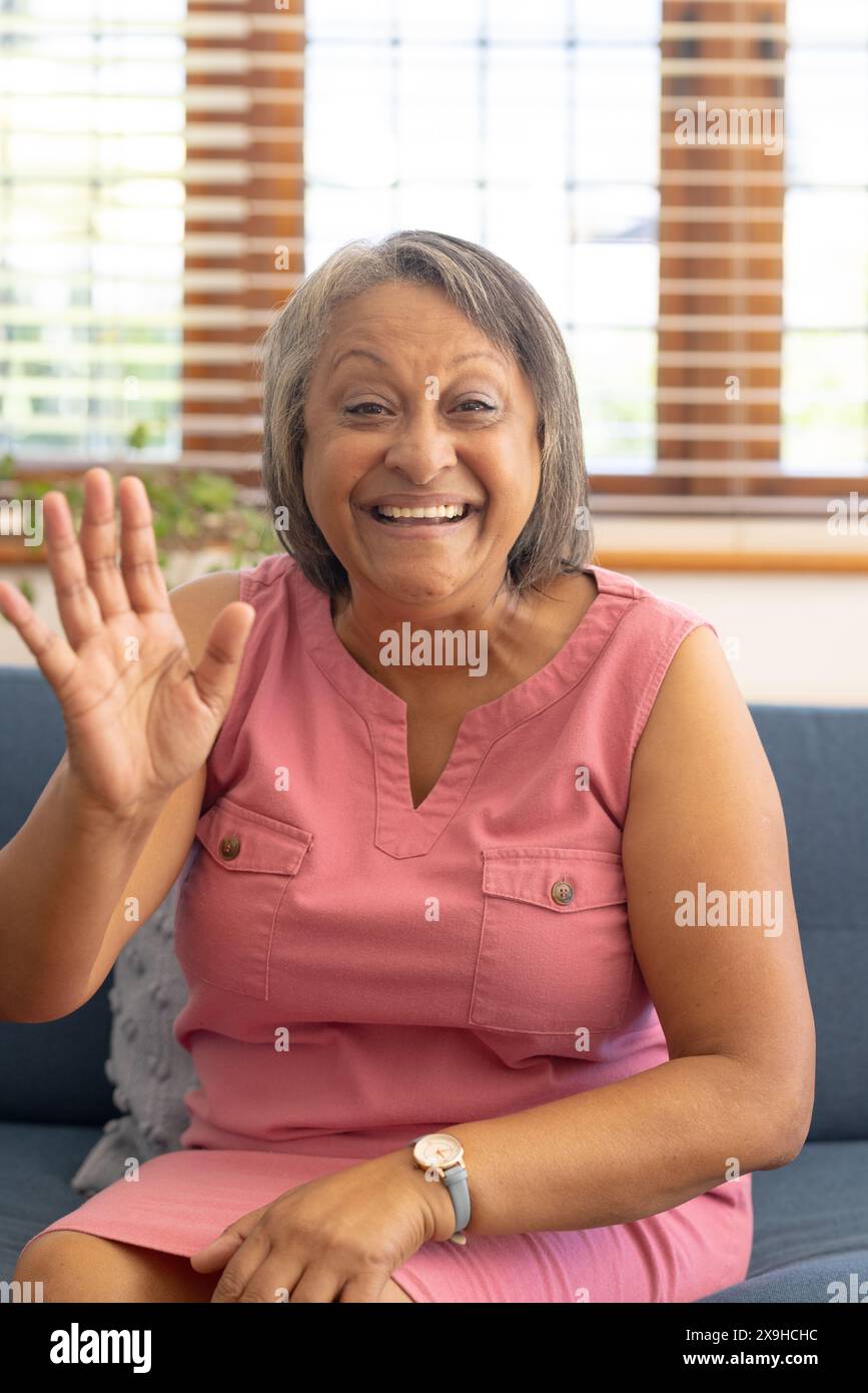 At home, biracial senior woman is smiling and waving during video call ...