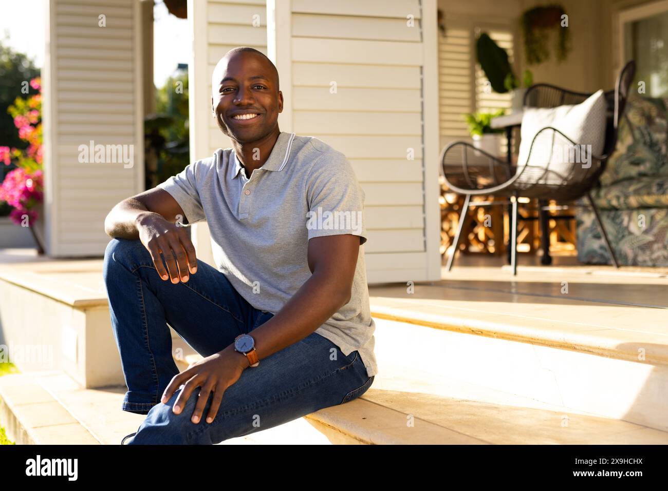 Outdoors, African American young man sitting on porch steps, smiling at ...