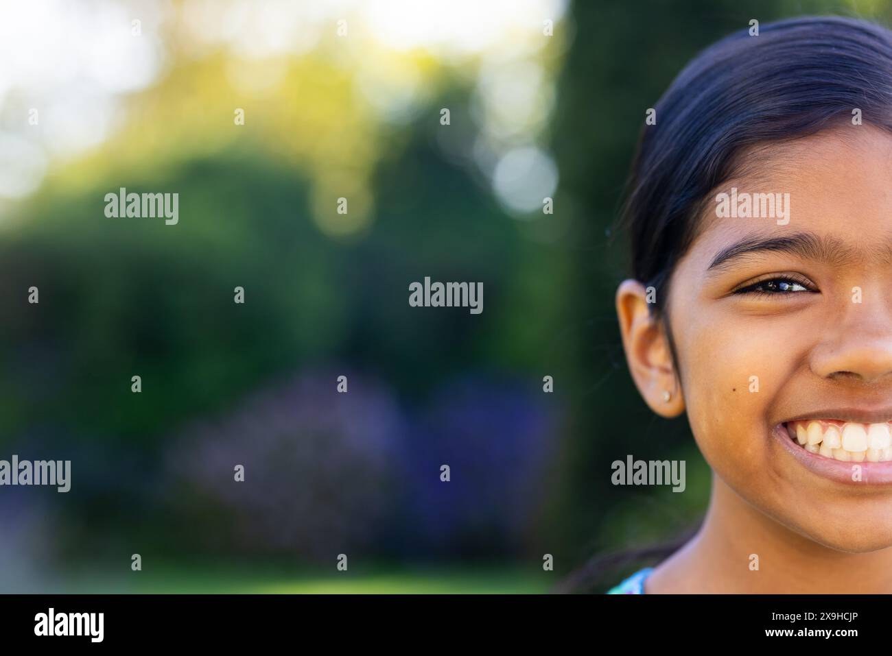 Outdoors, young biracial girl smiling brightly, showing her teeth, copy ...