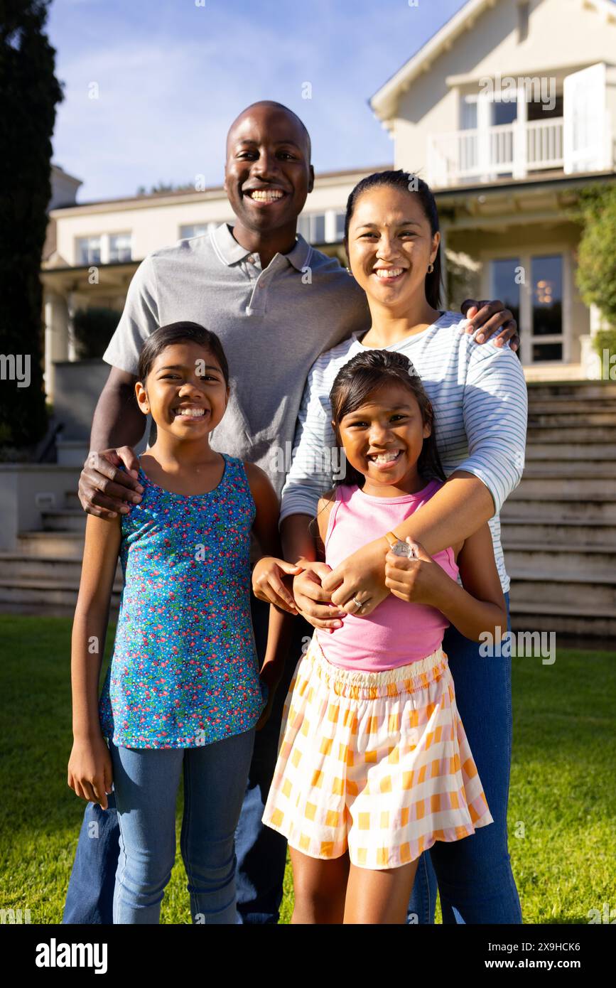 Outdoors, diverse family of four is smiling and posing together, in ...