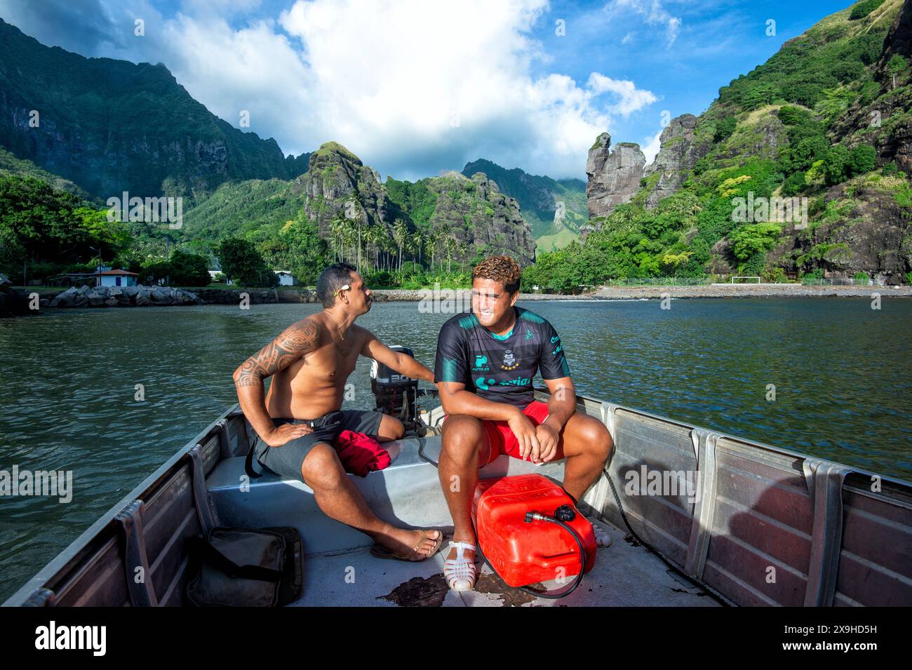 Two young Polynesian men driving a dinghy at the spectacular bay of ...