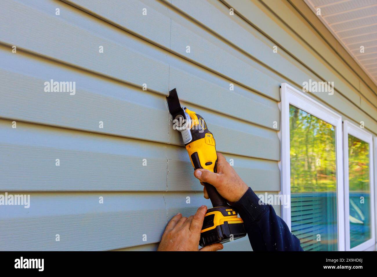 During reconstruction of house, multi tools damaged vinyl siding is cut ...