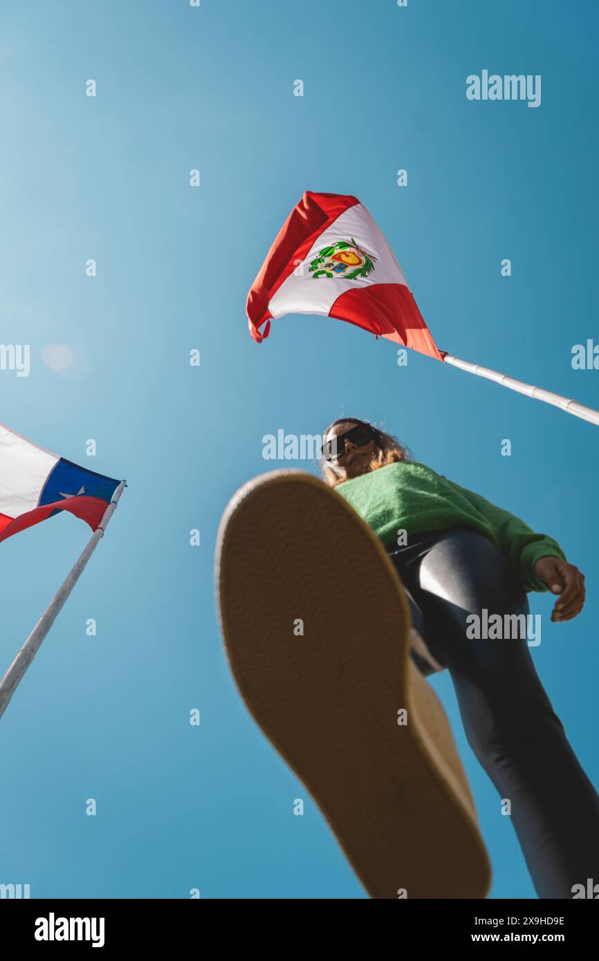 A woman walking towards two flags, the flags of Peru and Chile ...