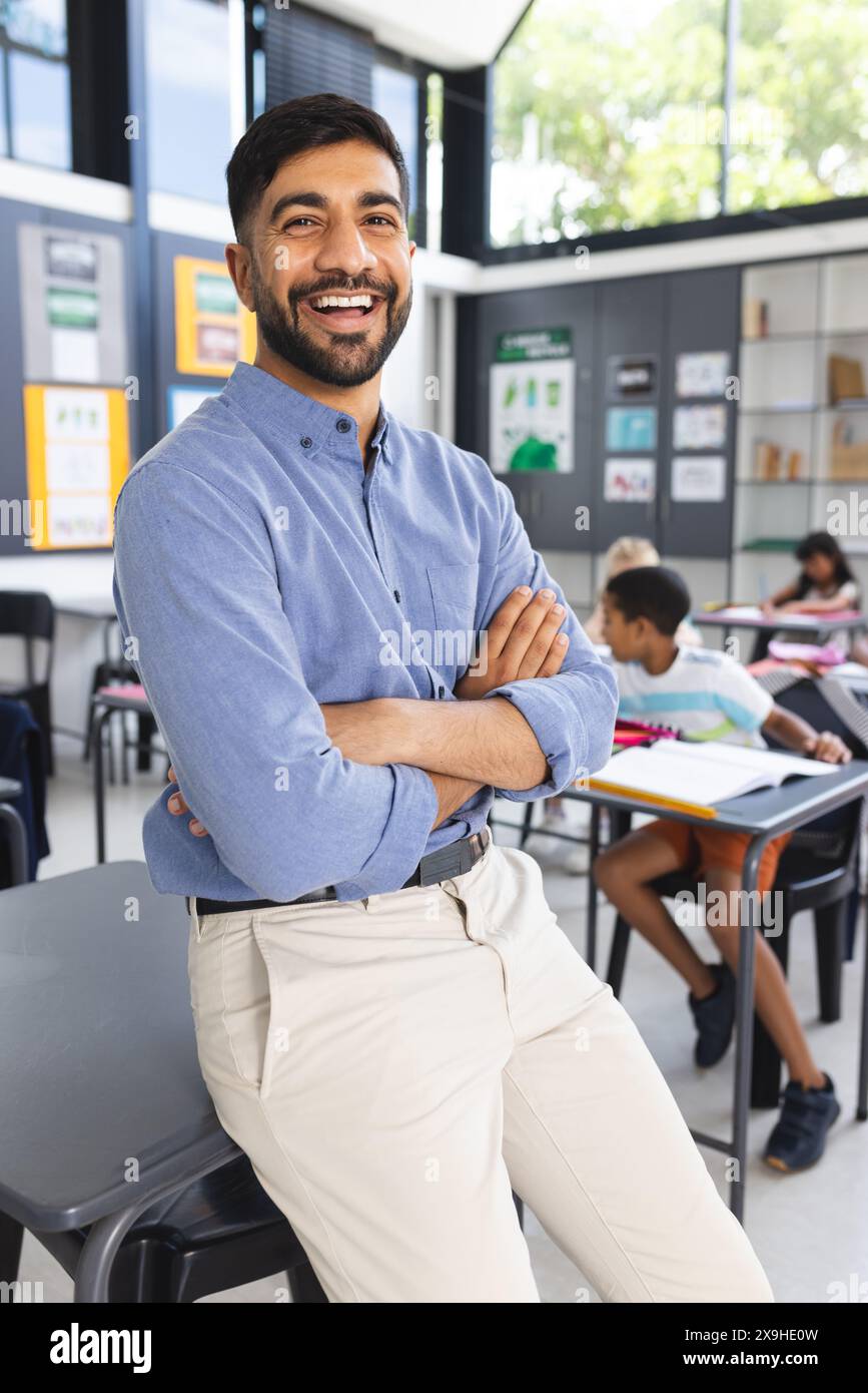 Young Asian male teacher with a beard smiles confidently in a school ...