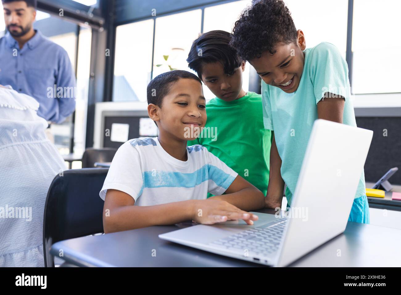 In school, diverse students are focusing on laptop in the classroom. Asian male teacher ...