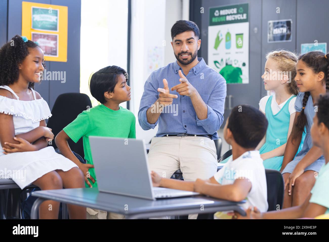 In school, Asian male teacher explaining to diverse group of young ...
