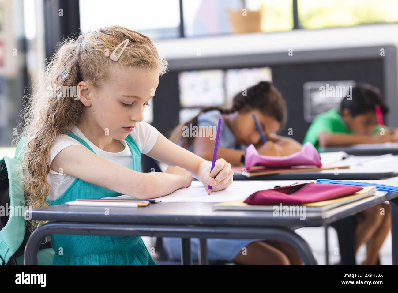 In school, diverse group of young students focusing on writing in the ...