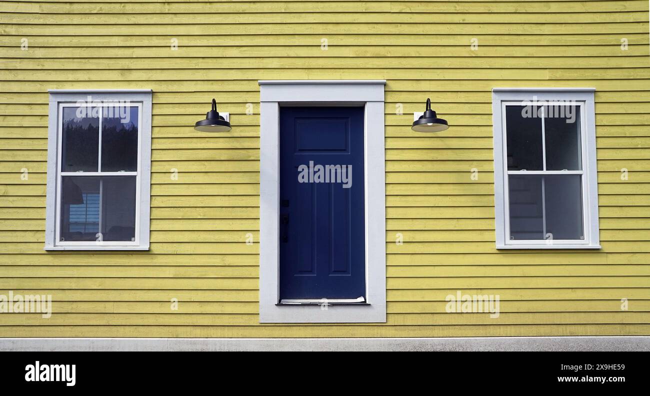 Facade of yellow clapboard house with door and two windows Stock Photo ...