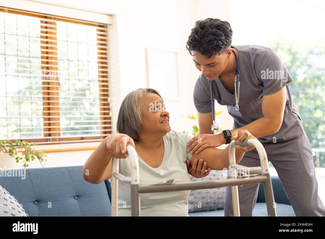 At home, a young biracial male nurse aids an elderly woman with her ...