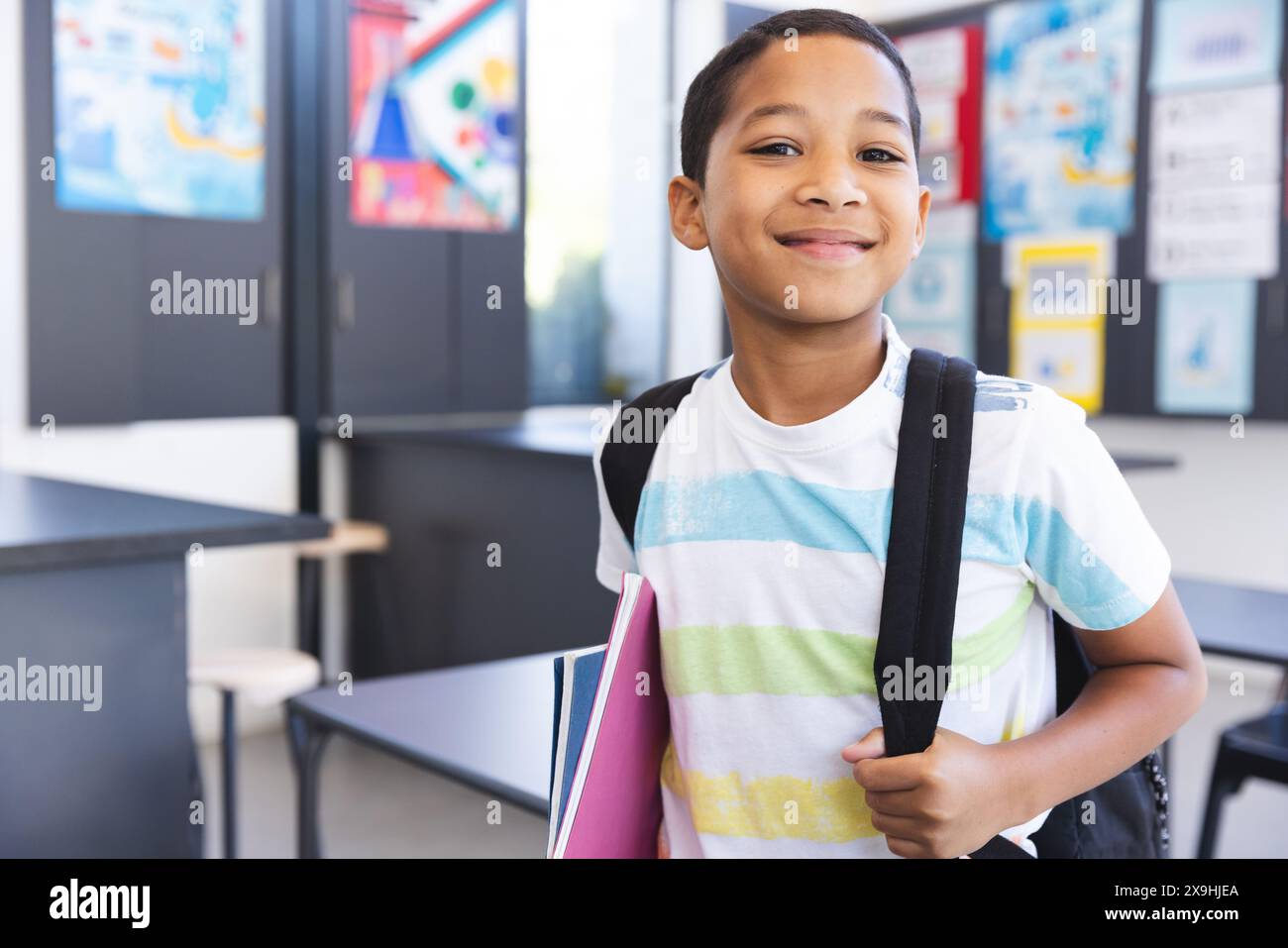 In a school setting, in a classroom, a young biracial student stands ...
