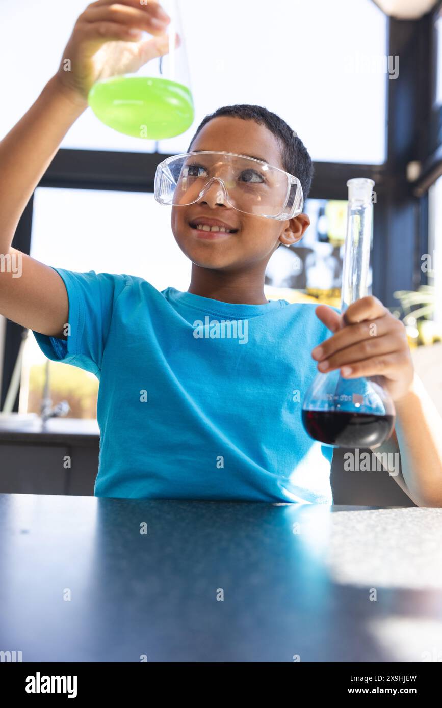 Biracial boy engages in a science experiment at school in the classroom ...