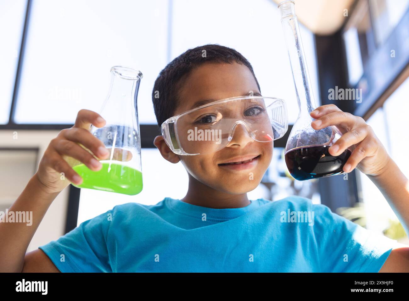 Biracial boy conducts a science experiment at school in the classroom ...
