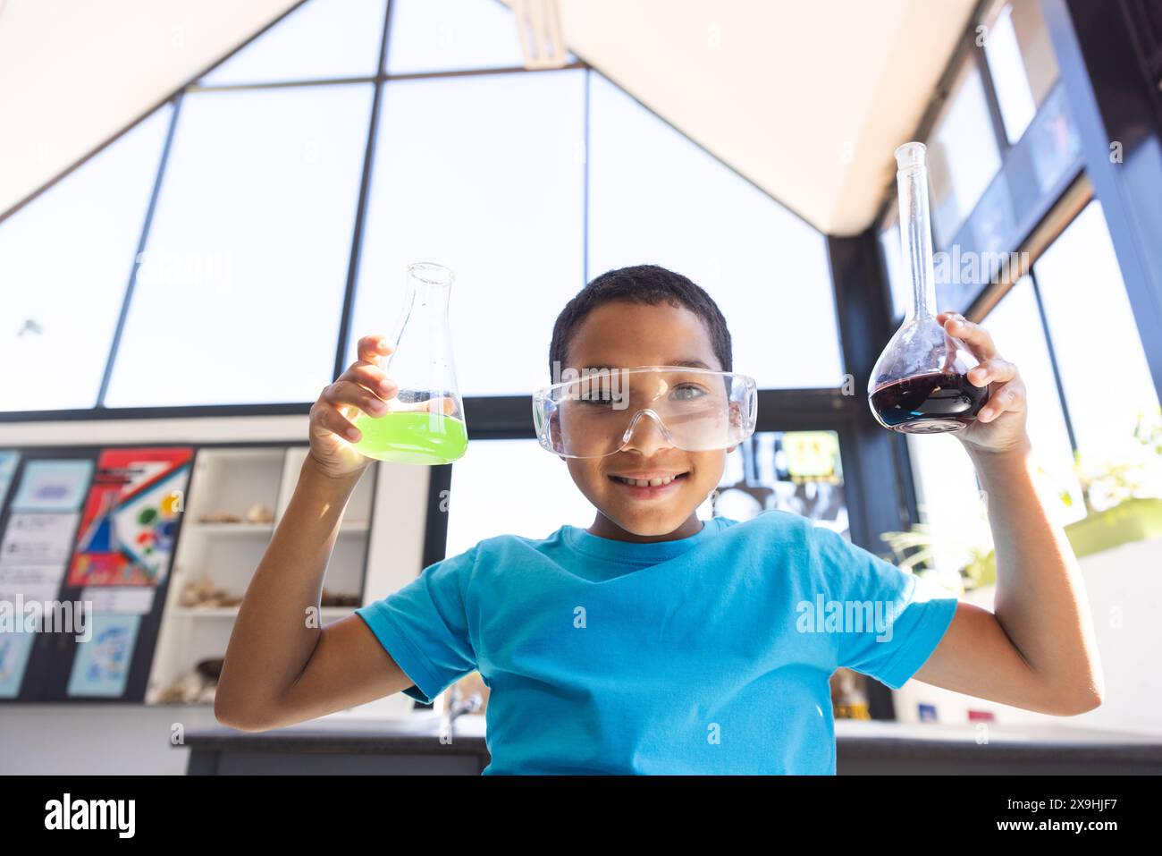 Biracial boy holds science beakers in a classroom. His excitement for ...