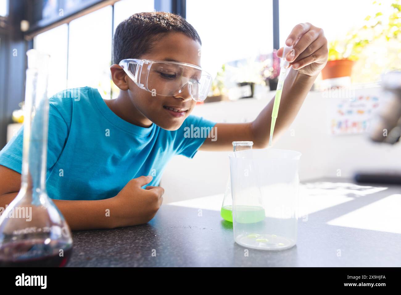 Biracial boy engaged in a science experiment at school in the classroom ...