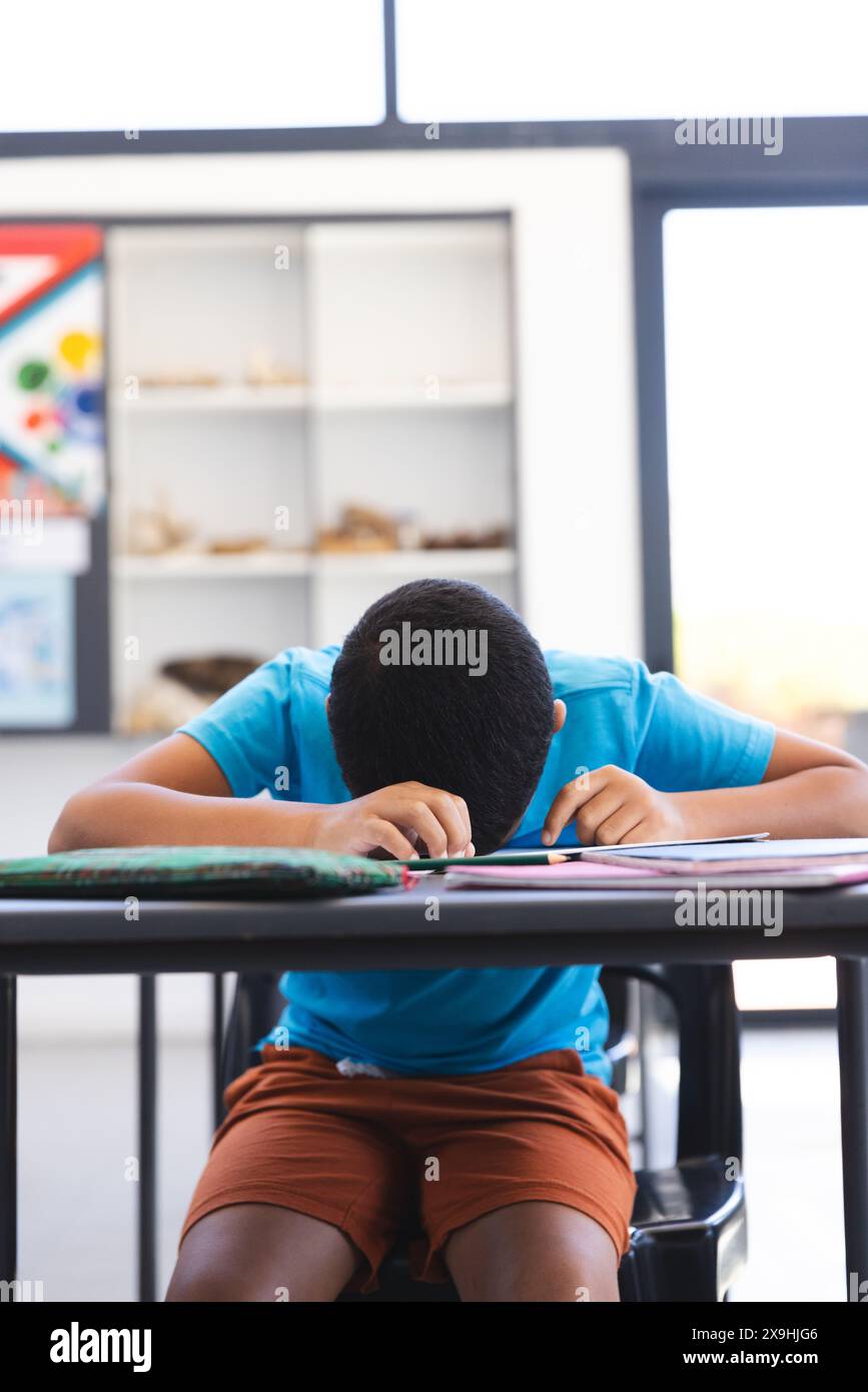 Biracial boy focused on drawing in the classroom at school Stock Photo ...