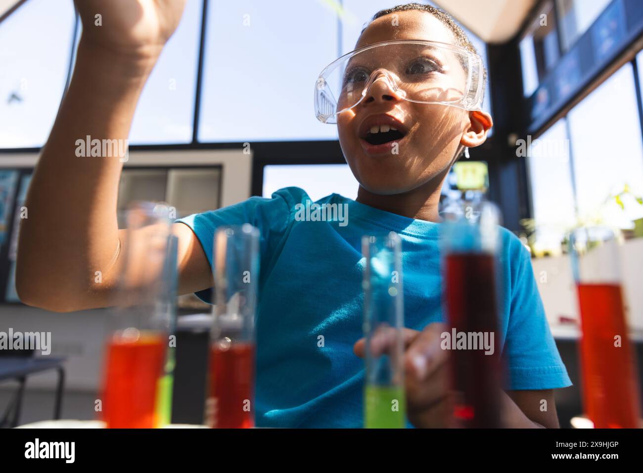 Biracial boy engages in a science experiment at school in the classroom ...