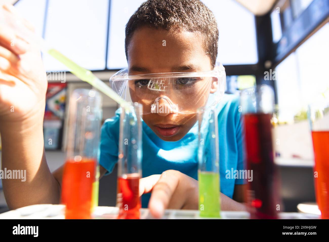 Biracial boy examines test tubes in a school lab. His focus on the ...