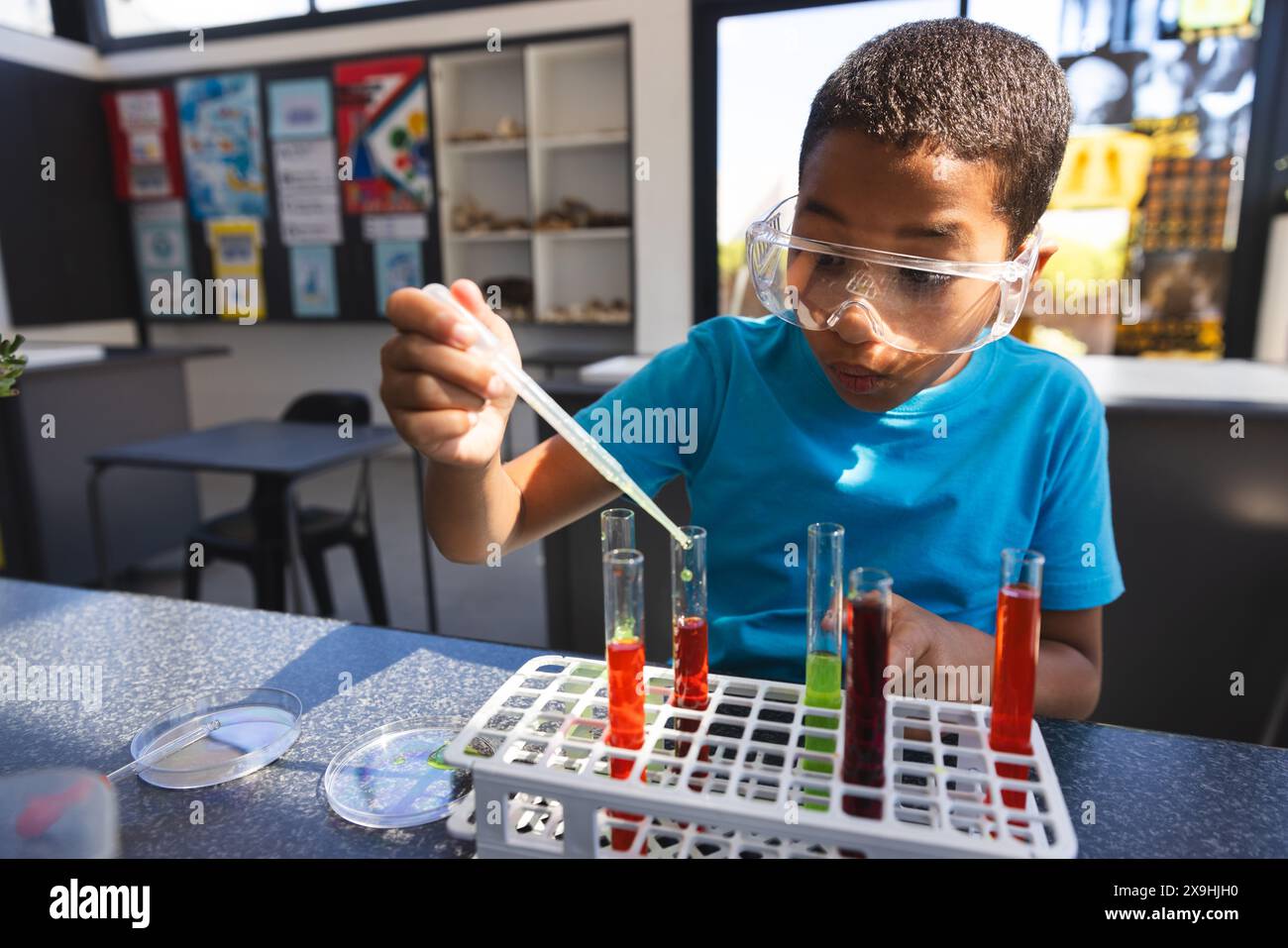 Biracial boy engages in a science experiment at school in the classroom ...