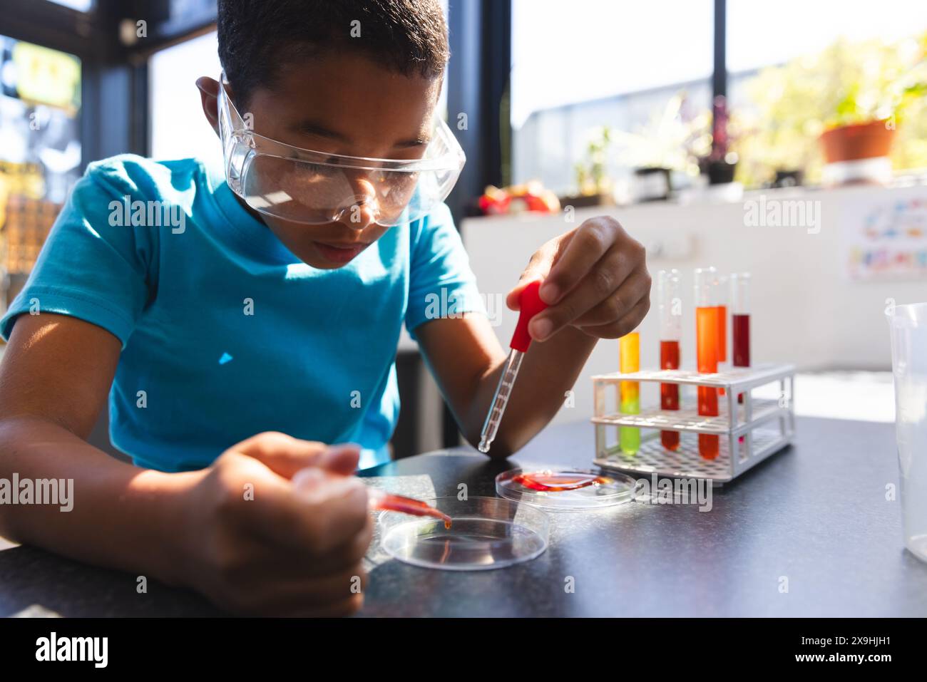Biracial boy engages in a science experiment at school in the classroom ...