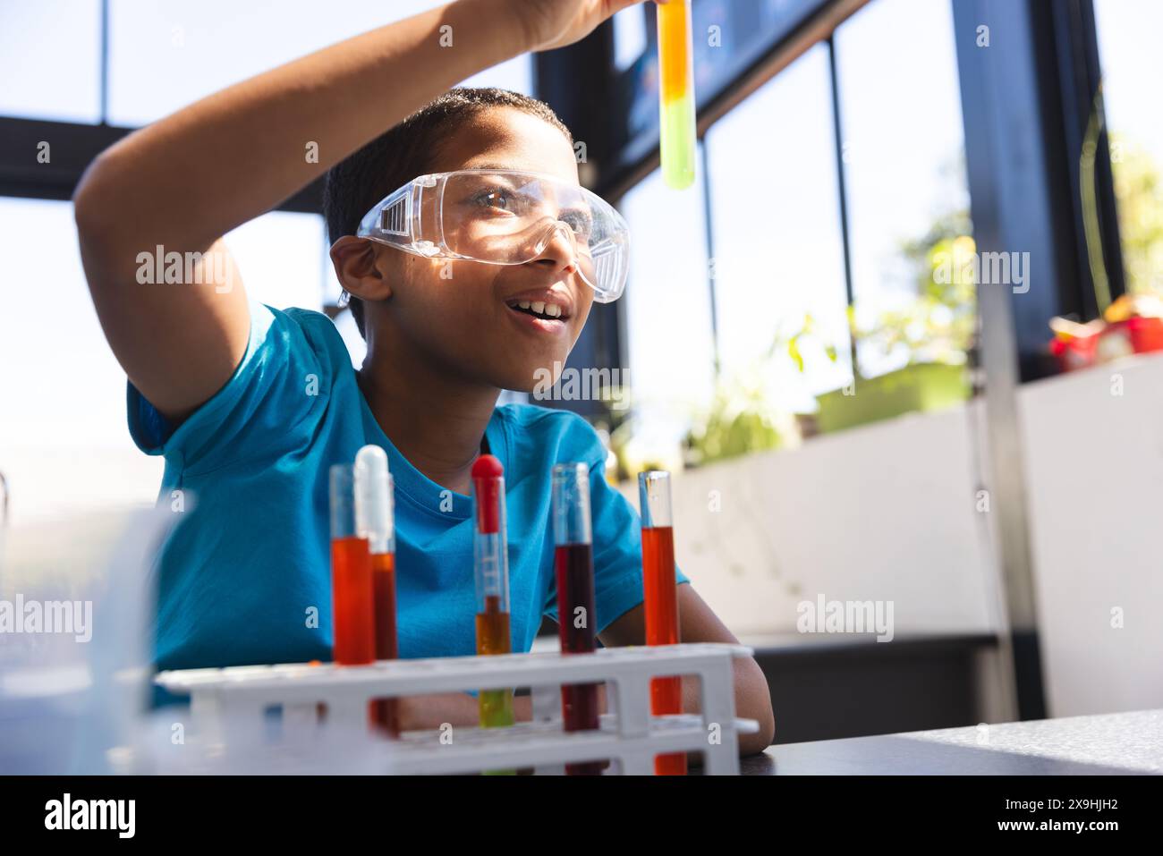 Biracial boy engages in a science experiment at school in the classroom ...